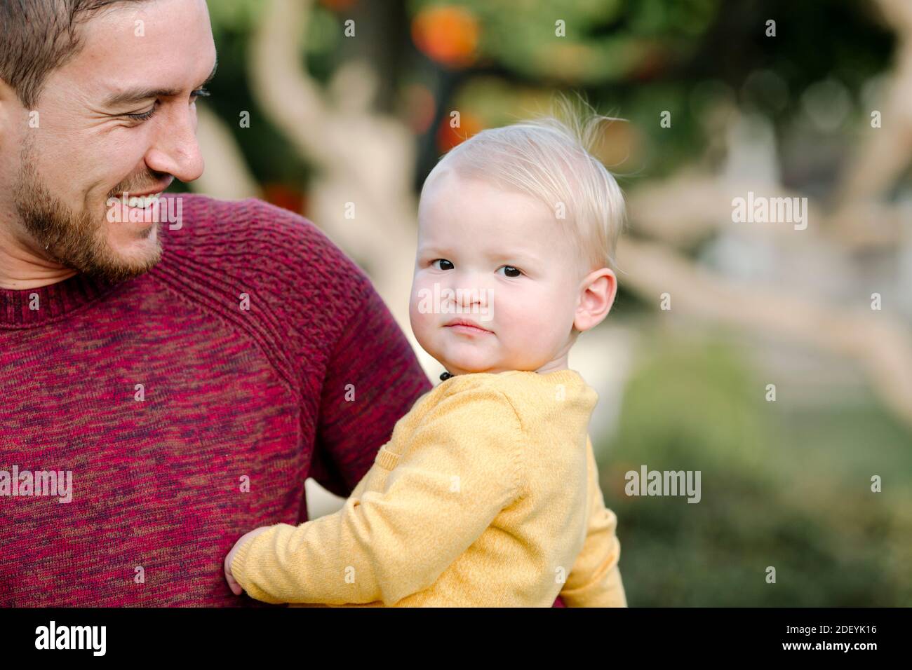 Beaming 30 yr old dad with beard holding blonde baby in yellow shirt ...