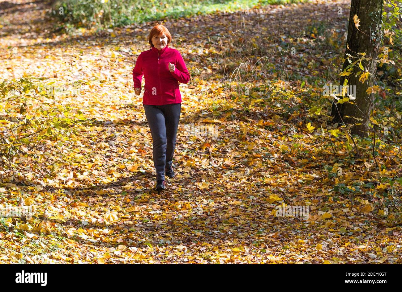 Active middle-aged woman jogs runs on nature Stock Photo - Alamy