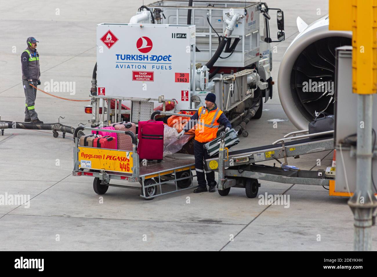 Aircraft ramp loader loading baggage to conveyor belt on airport apron ...