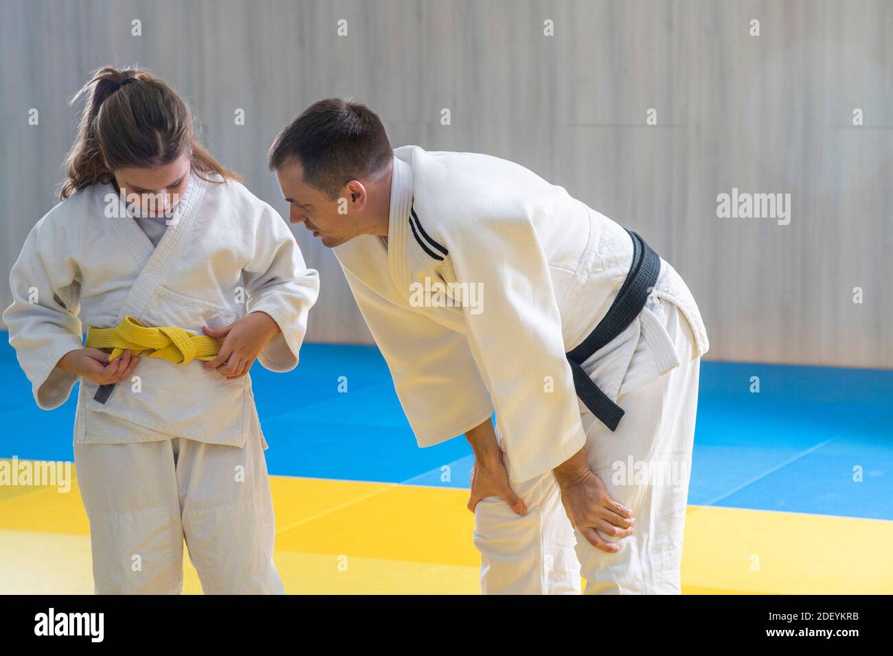 Experienced judo trainer with black belt tying belt for his pupil ...