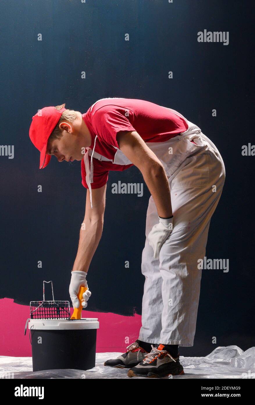 Man painting a wall. Painter in red overall painting wall in black ...