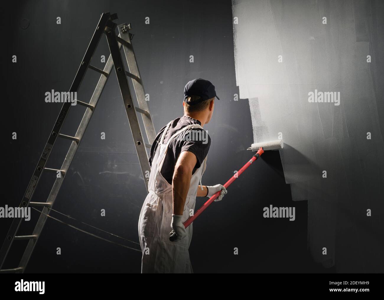 Male decorator painting a wall with white color Stock Photo - Alamy