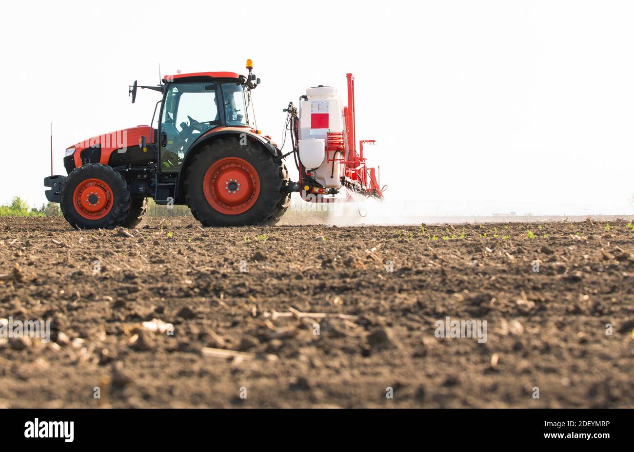 Tractor spraying pesticides on field with sprayer Stock Photo - Alamy