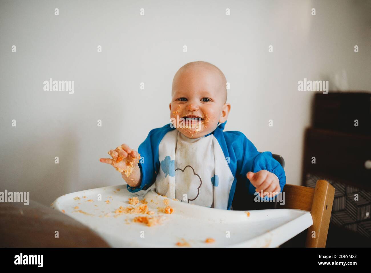 Cute baby smiling while eating food with his hands with dirty face ...