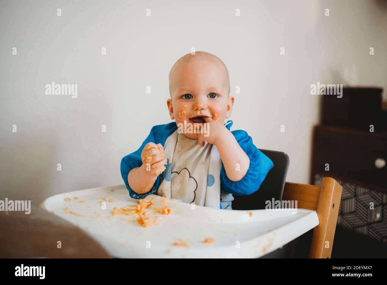 Adorable baby learning how to eat making a mess finger in mouth Stock ...
