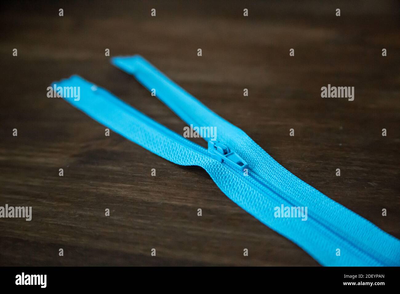 Blue zipper on dark wood background Stock Photo - Alamy