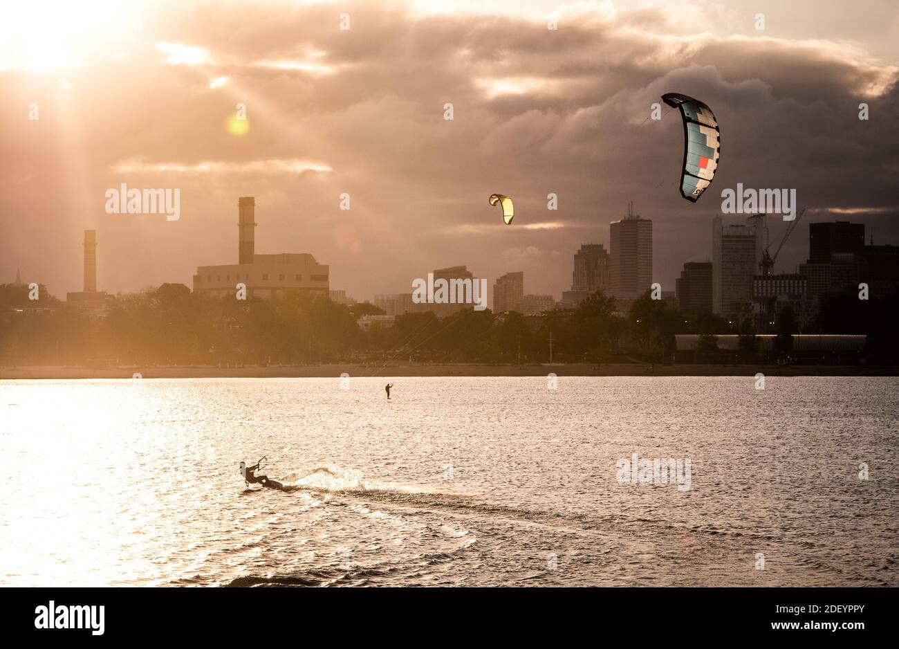 A woman kiteboarding on a summer evening with a dark Boston skyline ...