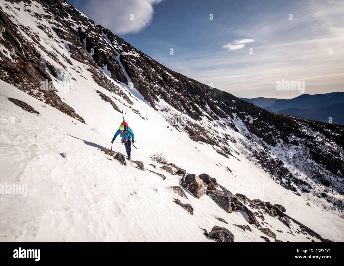 Climber walking through rocks on side of snowy mountain Stock Photo - Alamy