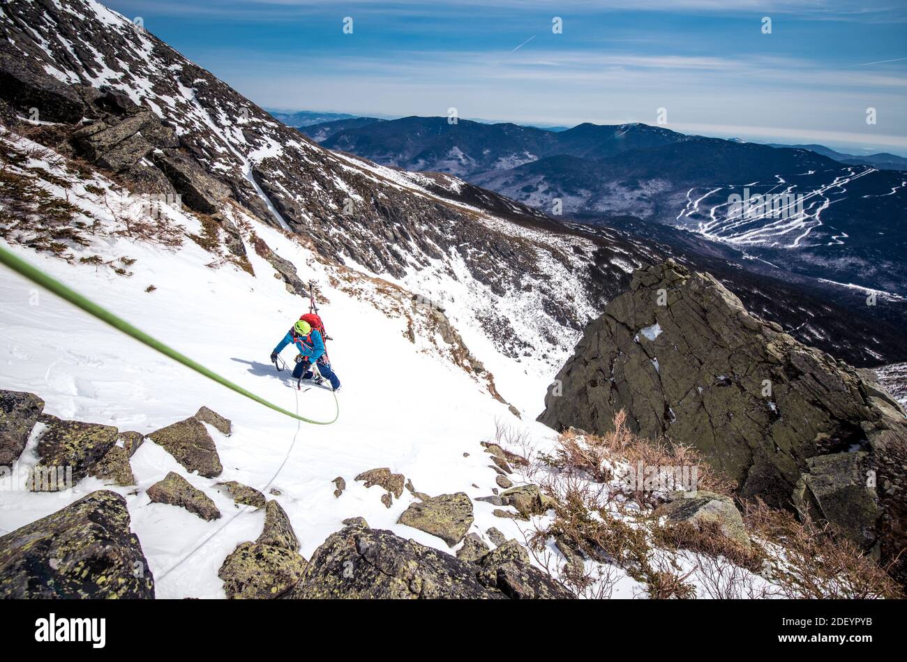 Man climbing steep snow gully with climbing rope and skis Stock Photo ...