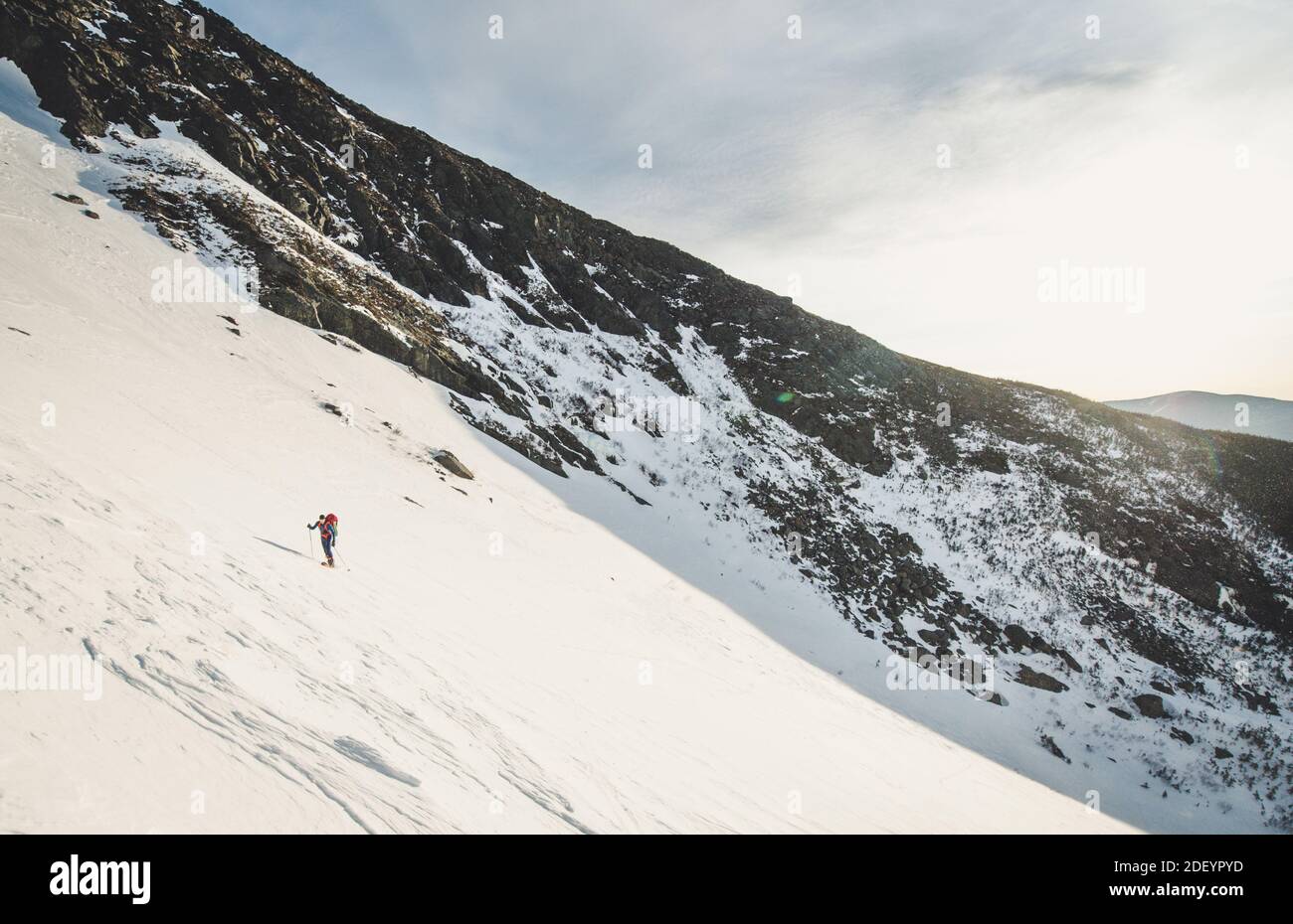 Skier ascends Huntington Ravine during sunrise in the White Mountains ...