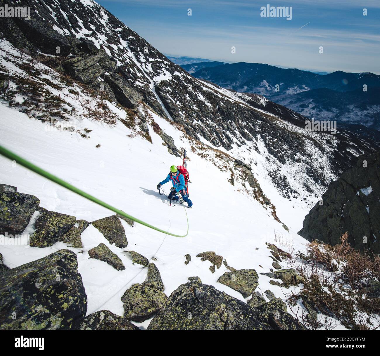 Man climbing steep snow gully with climbing rope and skis Stock Photo ...