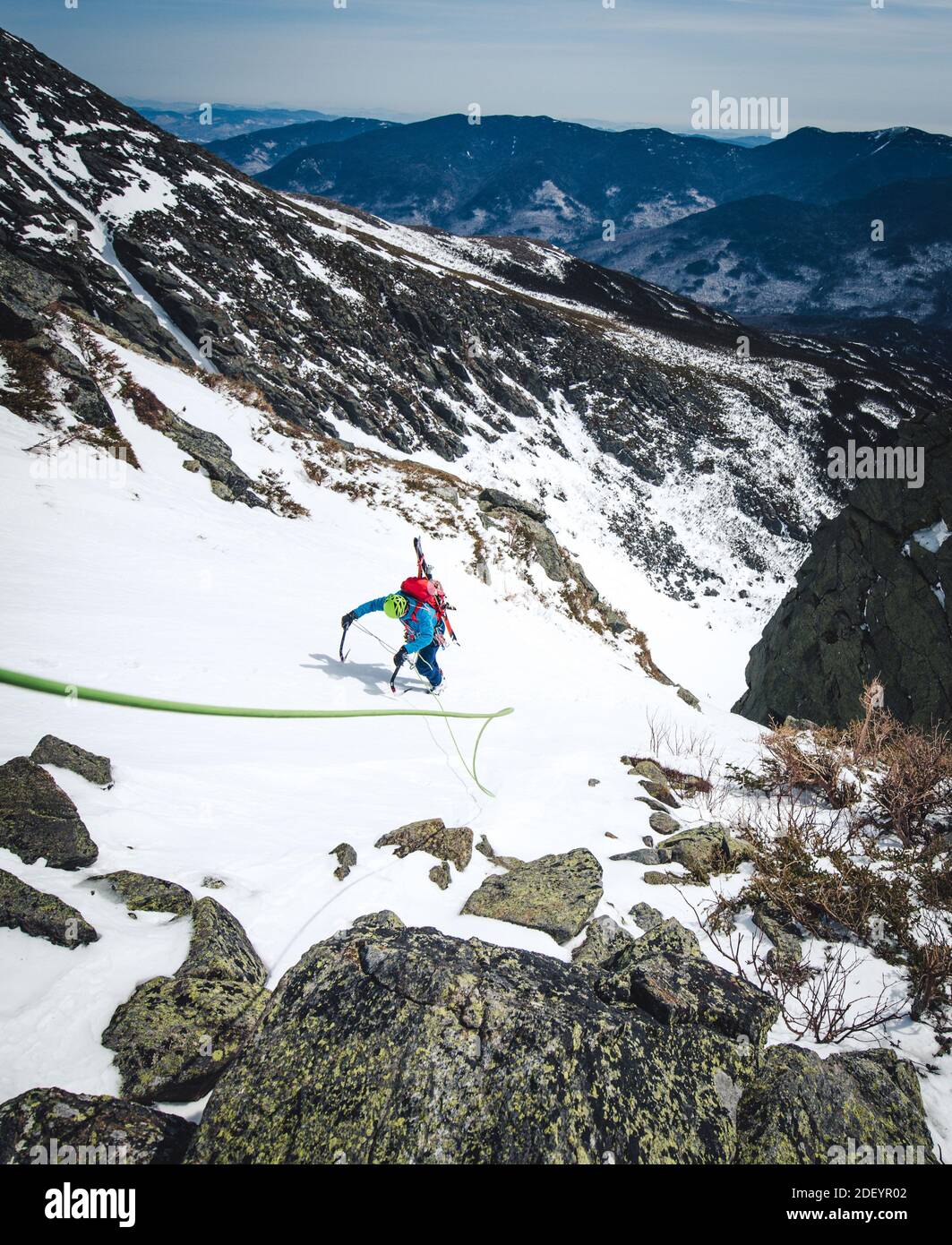 Man climbing steep snow gully with climbing rope and skis Stock Photo ...