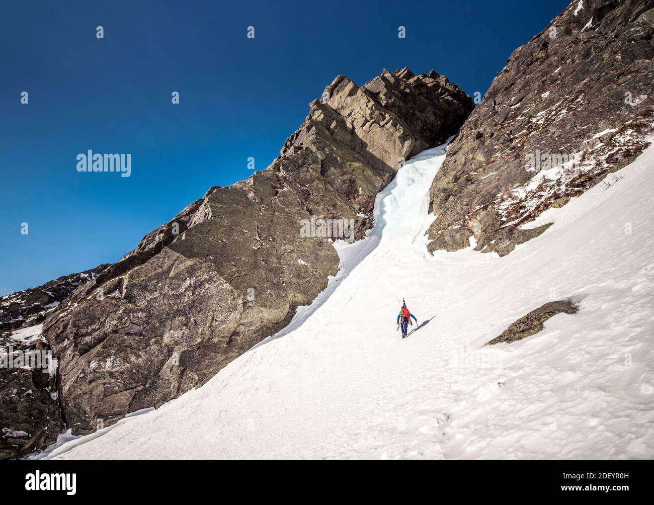Ice climber walking towards ice gully with skis on back Stock Photo - Alamy