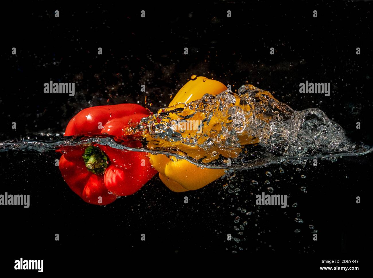 Red and yellow pepper splash into clear water Stock Photo - Alamy