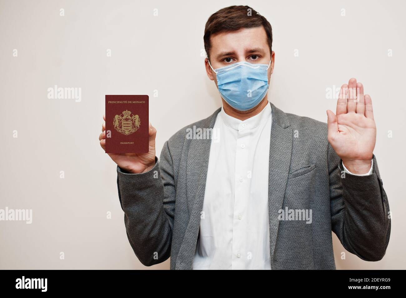 European man in formal wear and face mask, show Monaco passport with ...