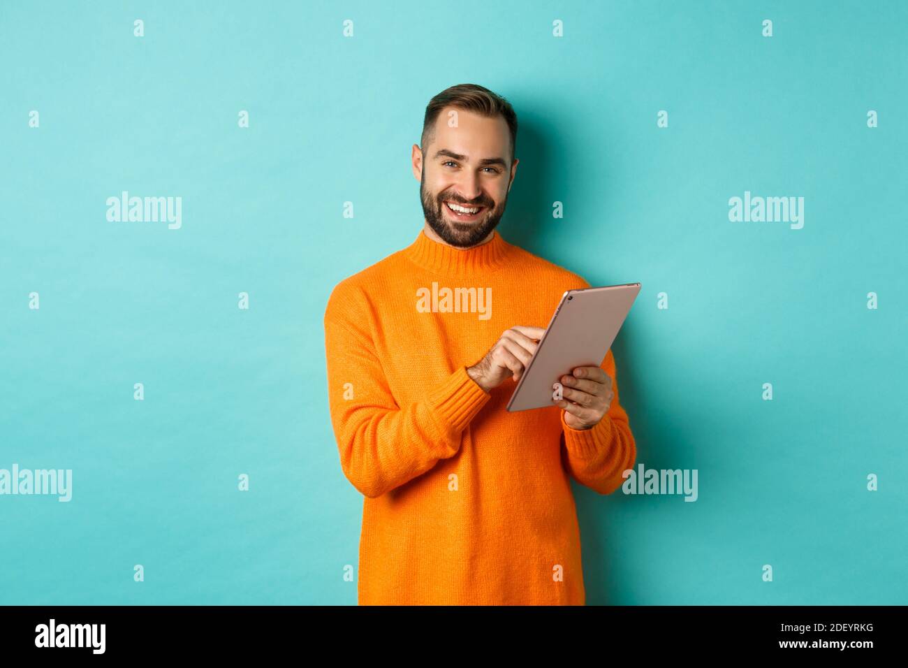 Handsome adult man using digital tablet and smiling, shopping online ...