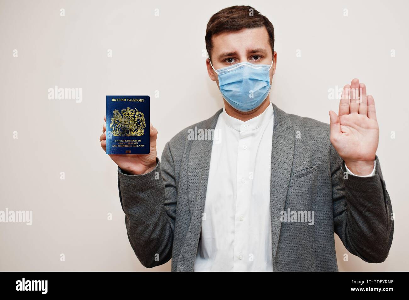 European man in formal wear and face mask, show United Kingdom passport ...