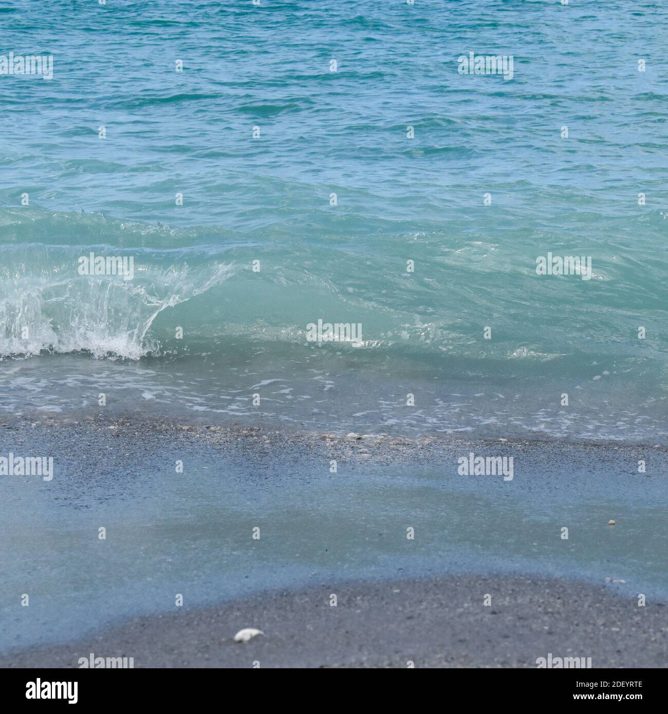 Turquoise wave breaking on shore Stock Photo - Alamy