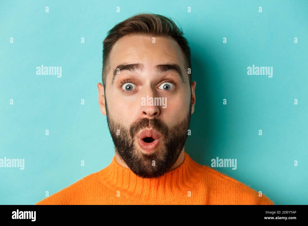 Headshot of handsome caucasian man with beard standing in orange ...