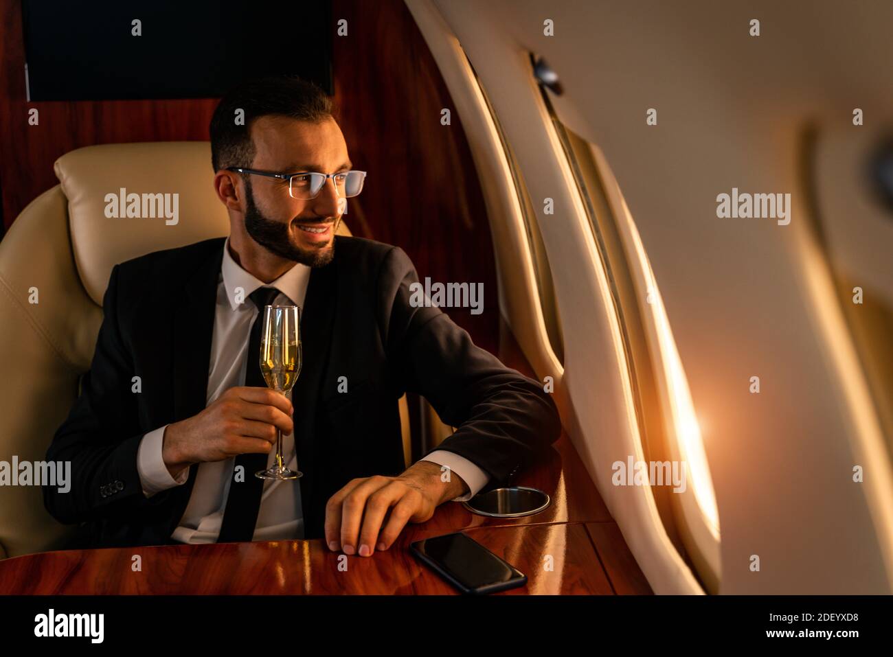 Handsome businessman wearing elegant suit flying on exclusive private ...