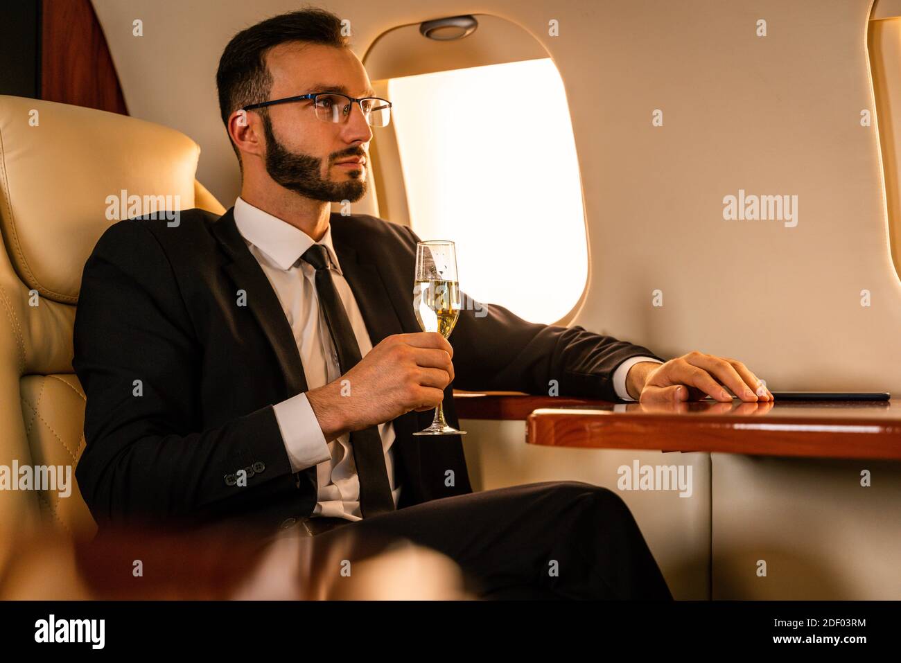 Handsome businessman wearing elegant suit flying on exclusive private ...