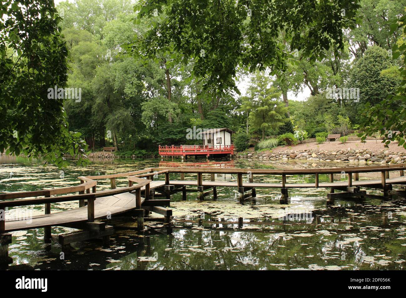 A viewing platform and a wood bridge over a lake surrounded by trees ...
