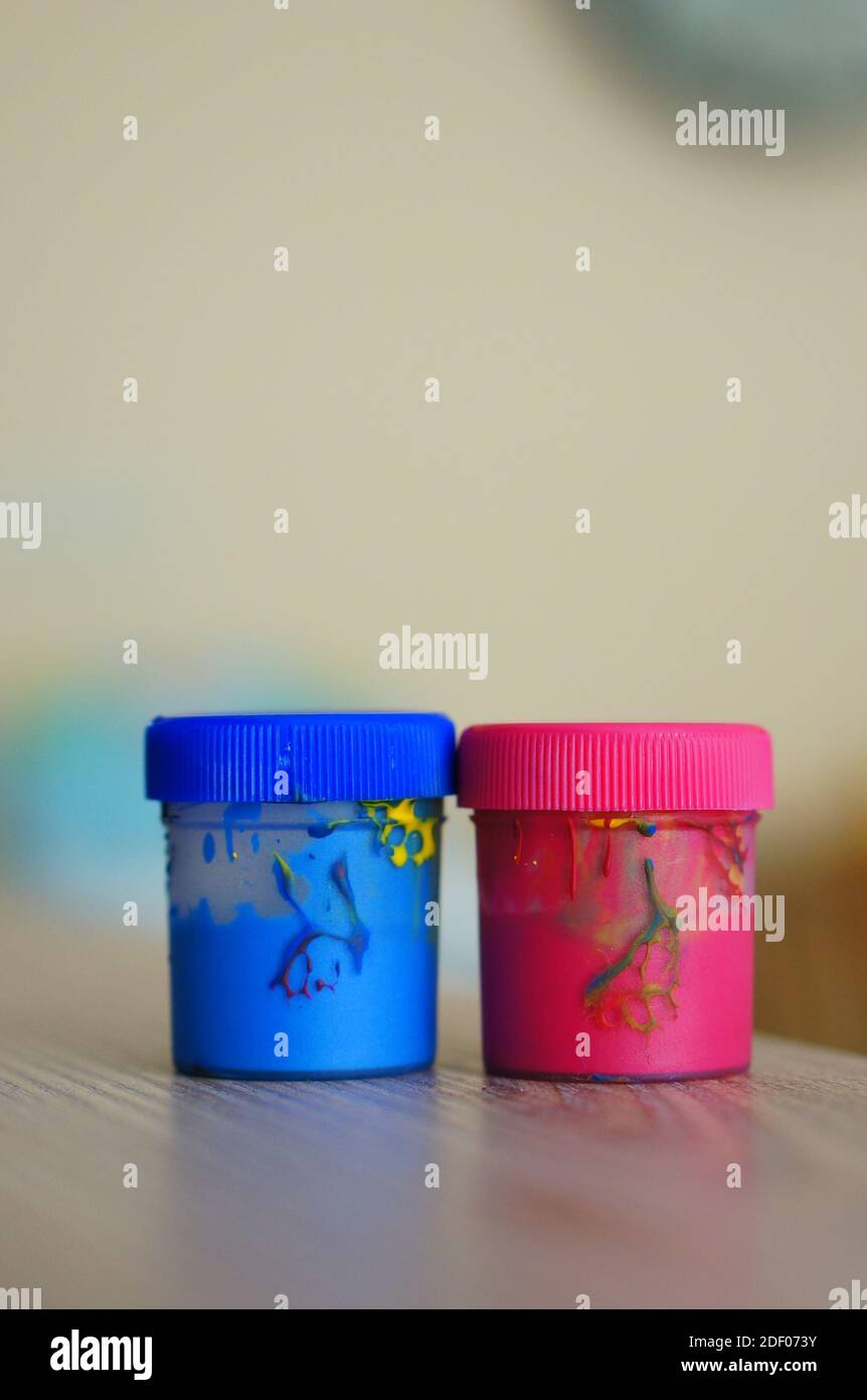 A vertical selective focus shot of small red and blue paint containers ...