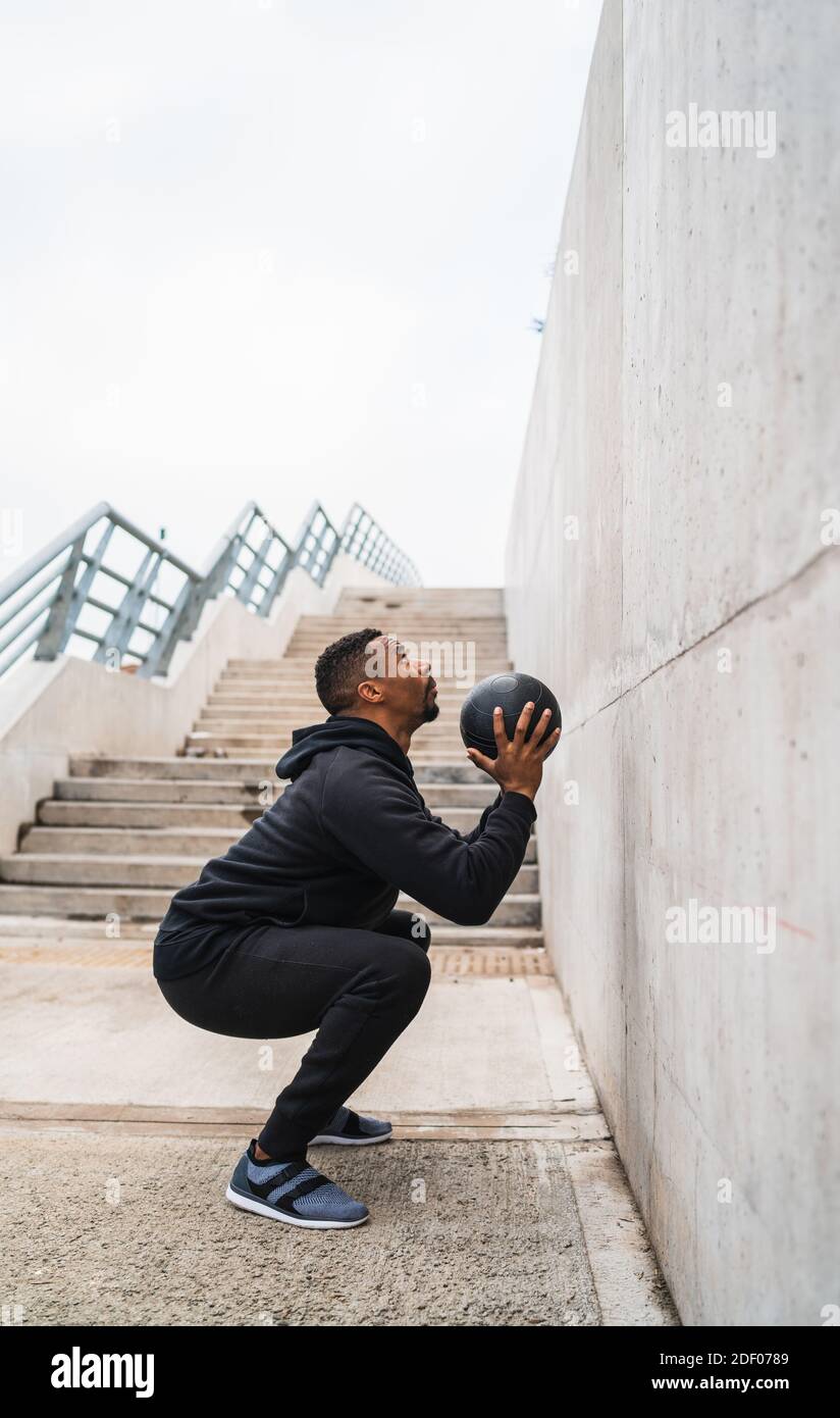 Athletic man doing wall ball exercise Stock Photo - Alamy