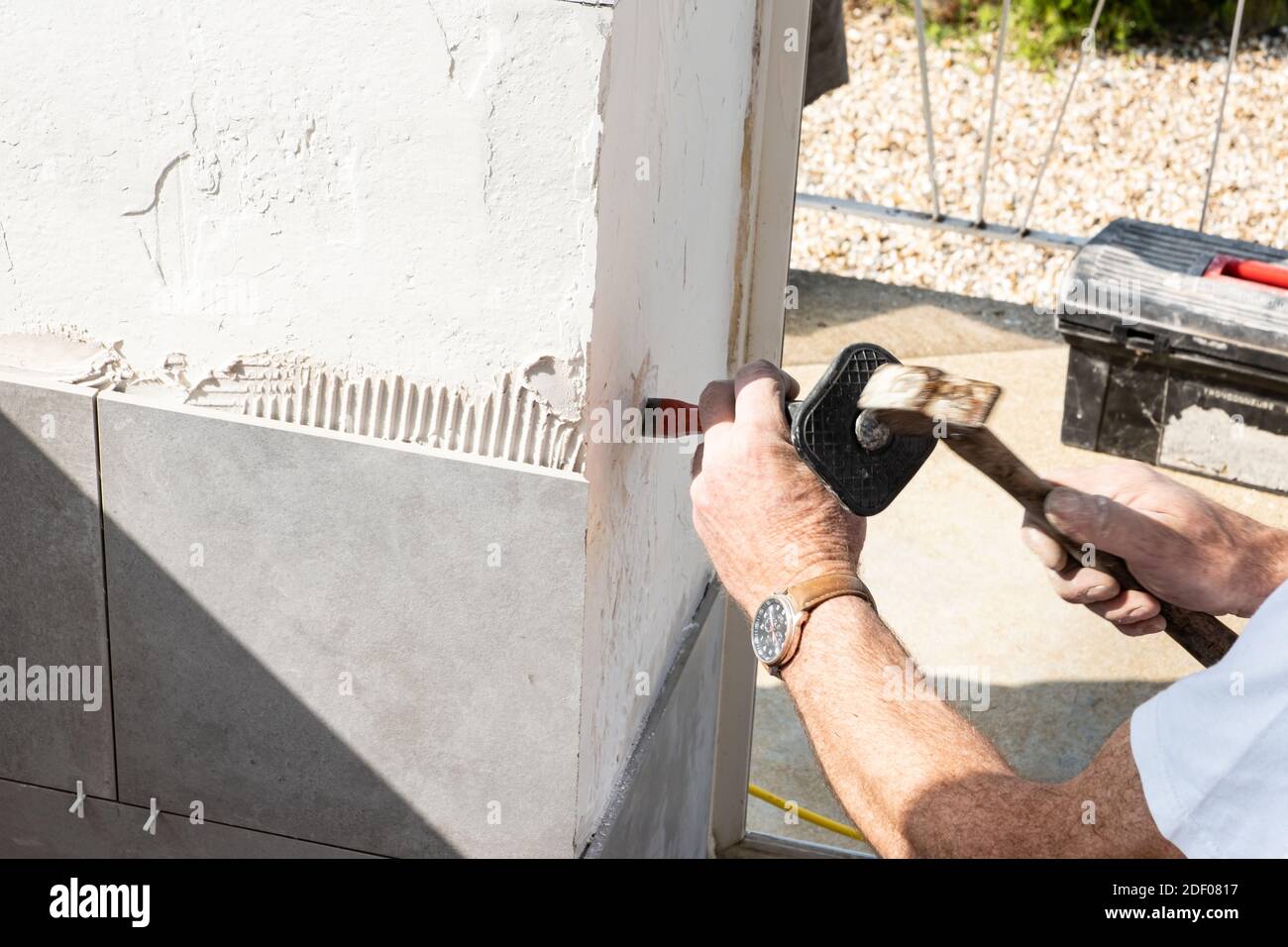 the mason prepares the wall with a chisel before laying a ceramic tile ...