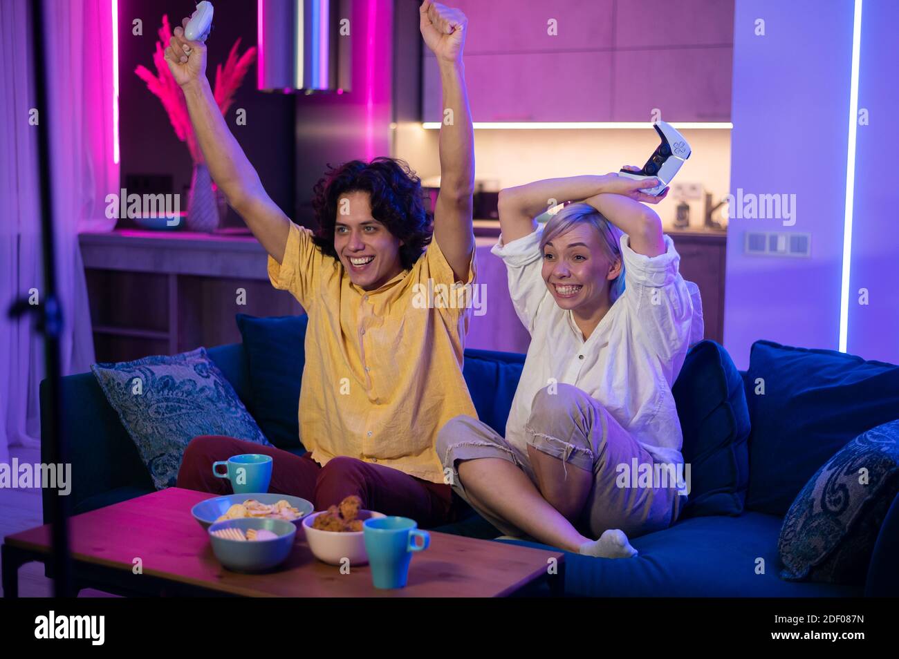 Millennial couple play video games together at home. Man and girl ...