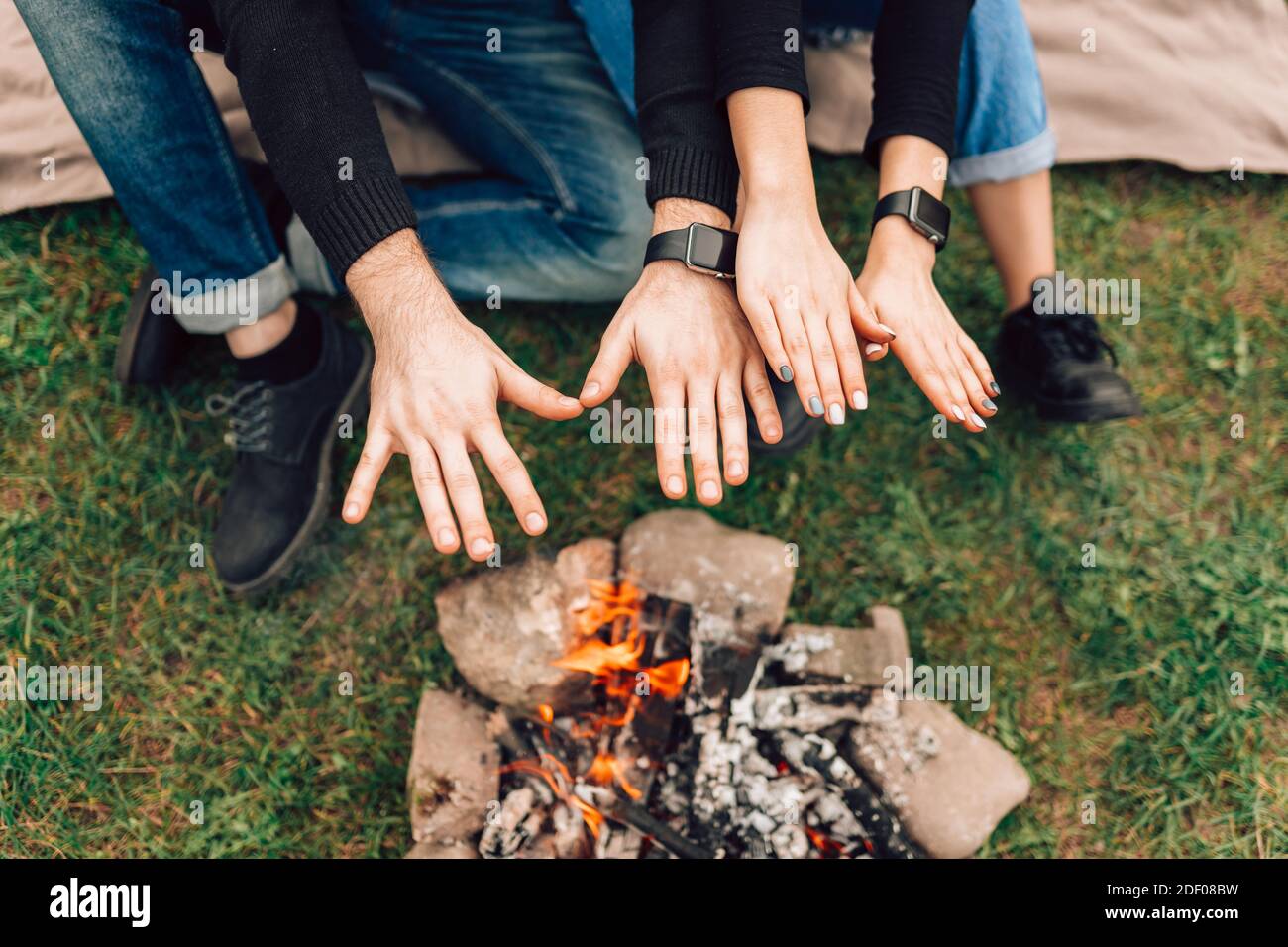 Romantic couple warming their hands over bonfire Stock Photo - Alamy