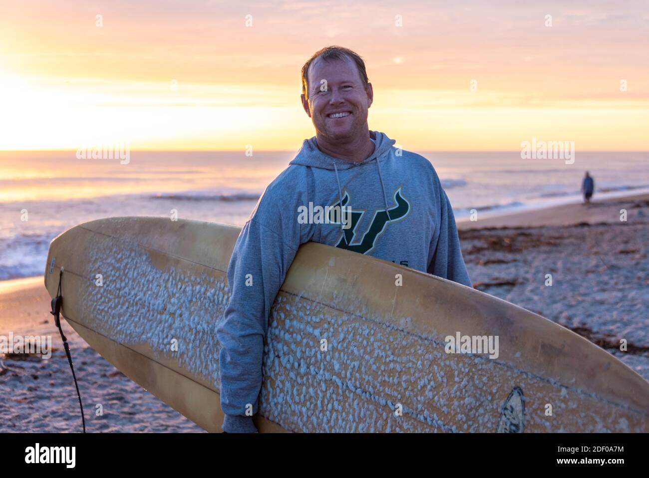 Florida surfer with longboard on the beach after a sunrise surf session ...