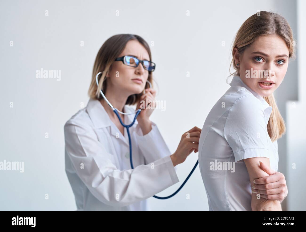 Professional doctor woman with stethoscope and female patient side view ...