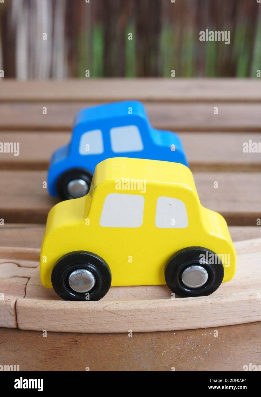 A vertical selective focus shot of two blue and yellow toy cars on a ...