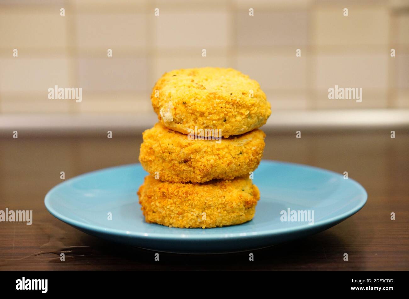 A soft focus of a stack of breaded fish burgers on a blue plate Stock ...