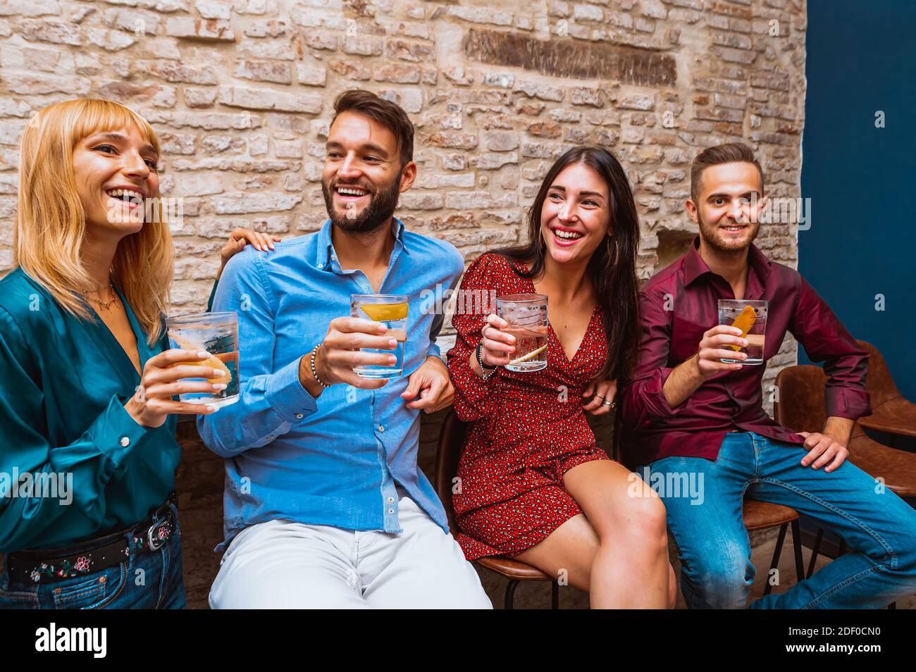 Happy smiling friends drinks gin tonic at night bar - New normal ...