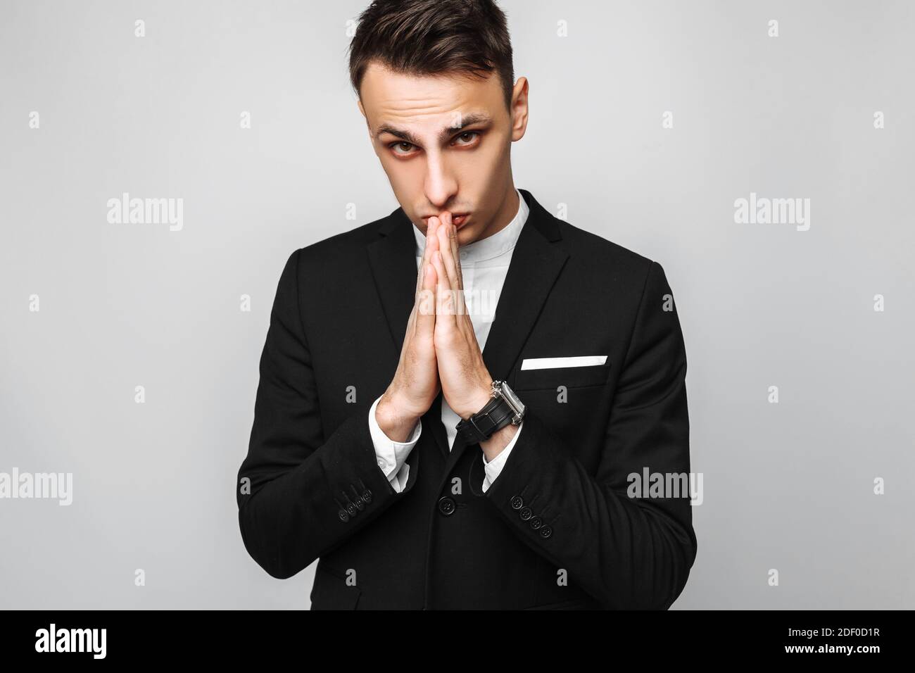Portrait of a promising businessman praying. A young guy in a black ...