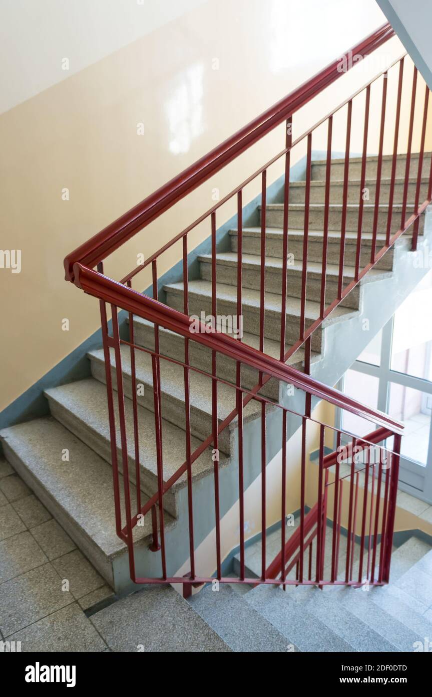 A vertical image of a staircase with red handrails Stock Photo - Alamy