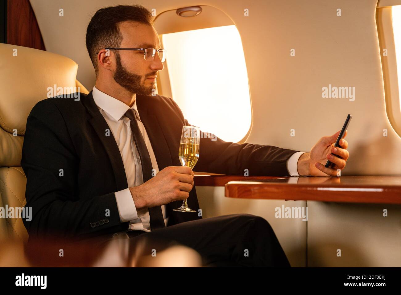 Handsome businessman wearing elegant suit flying on exclusive private ...