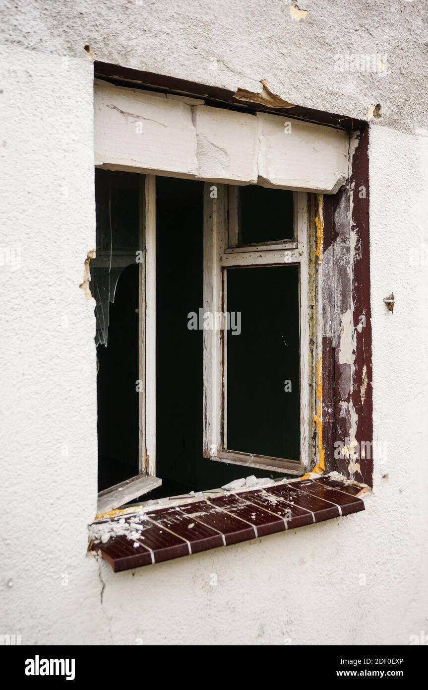 A vertical closeup shot of a white old house with an open window ...