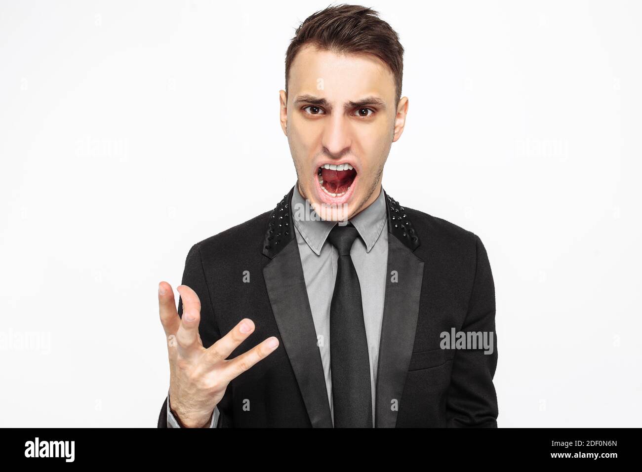 An angry depressed man dressed in a black suit yells angrily at someone ...