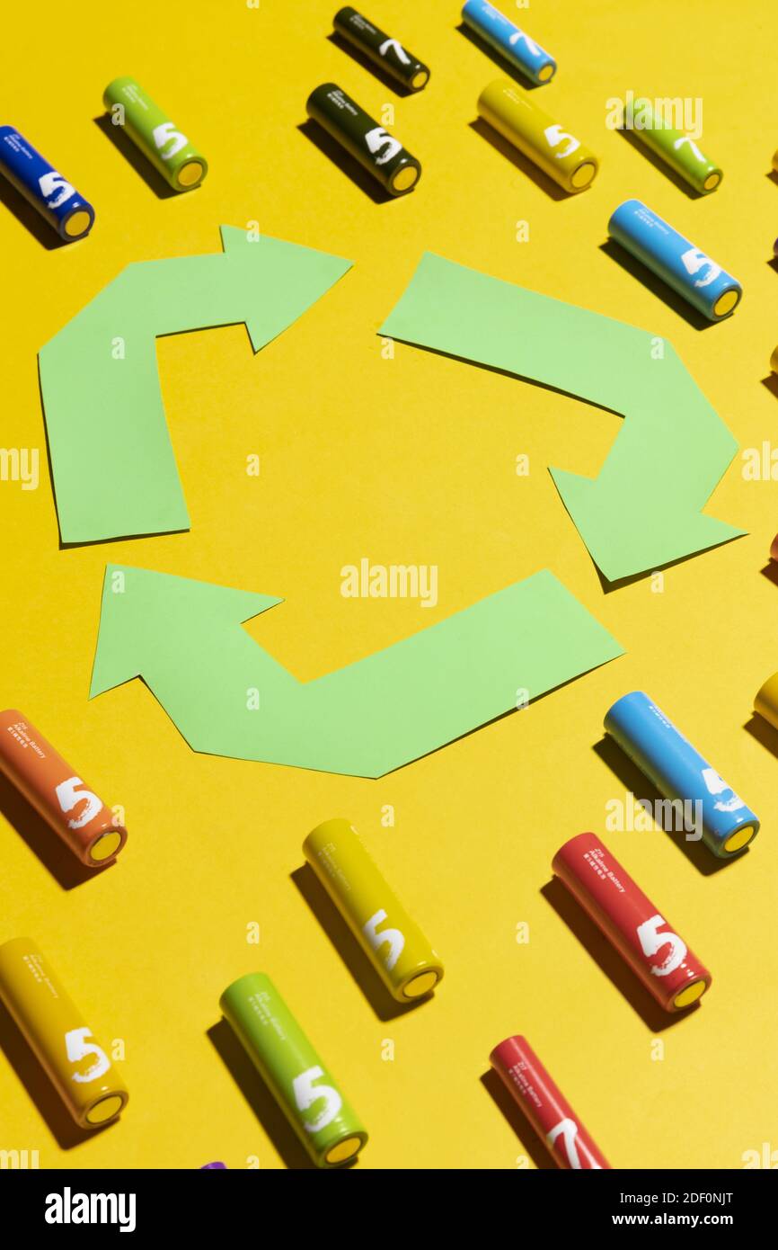 A vertical shot of batteries on a yellow background with a recycling ...