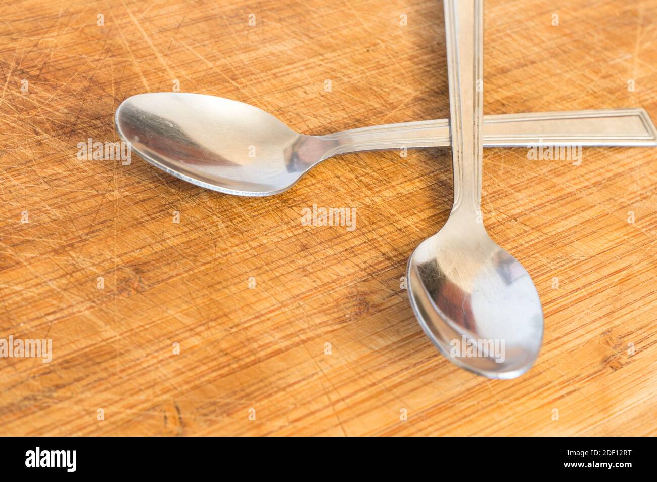 A closeup shot of two silver spoons on a wooden table Stock Photo - Alamy