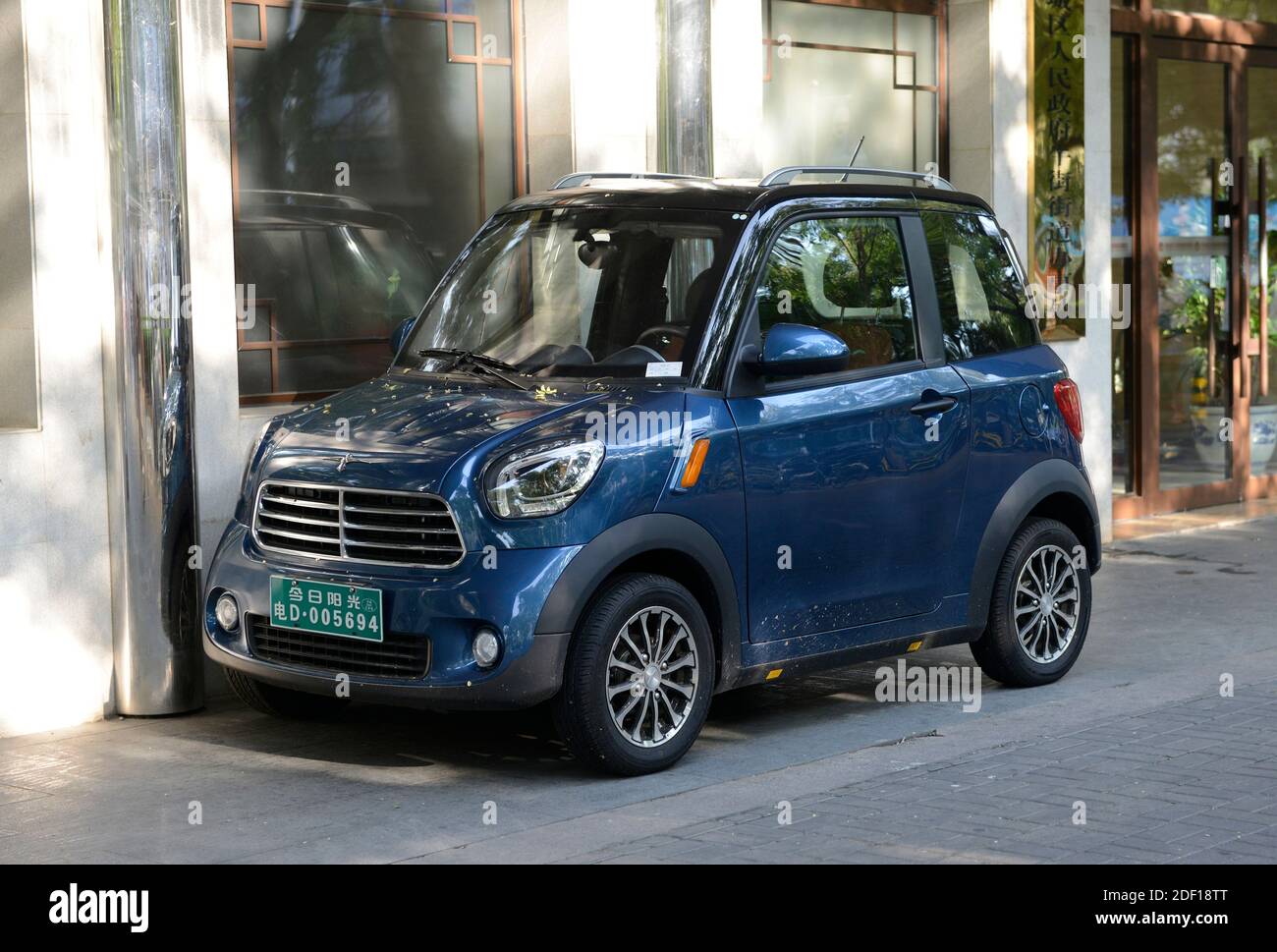 A small domestic branded and manufactured electric car parked by a shop ...