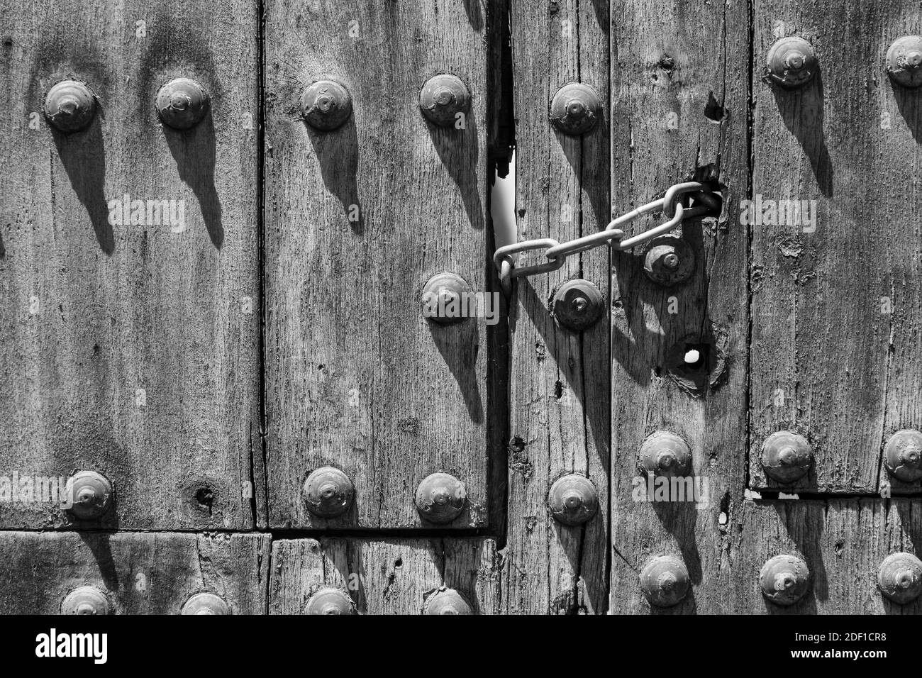 Chain lock on old wooden door with round rivets. Gate closed, no entry ...