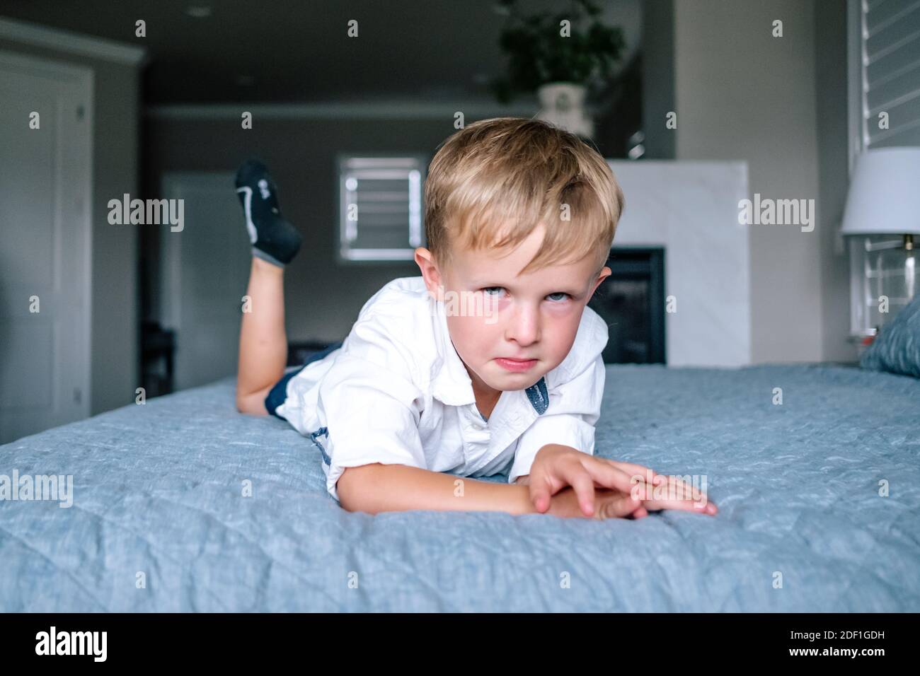 Preschool aged boy with angry face laying on a large bed Stock Photo ...