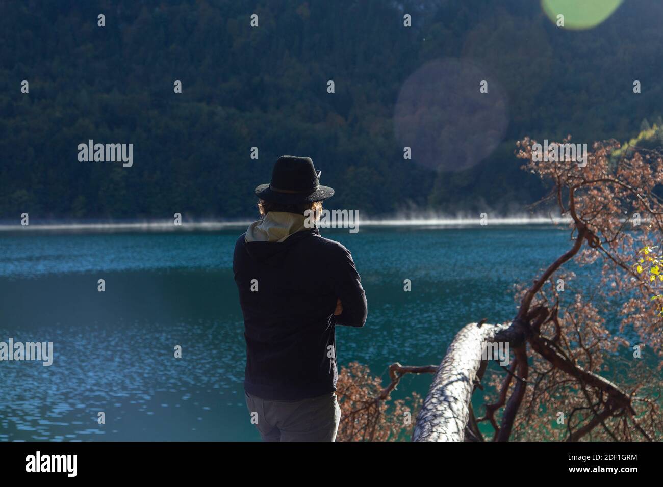 A hatted man looking across a clear alpine lake in Germany Stock Photo ...