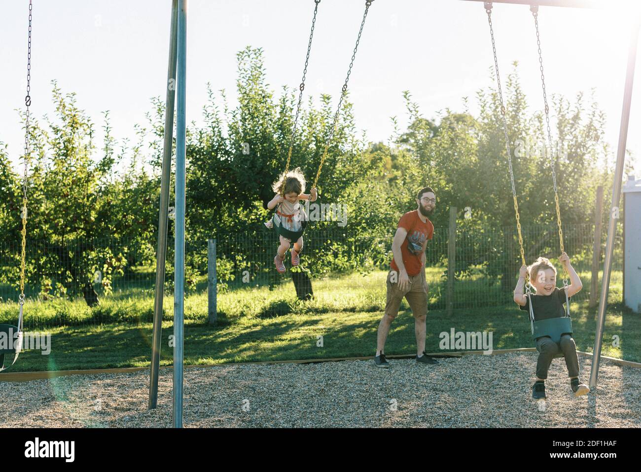 Man pushing child on swing hi-res stock photography and images - Alamy