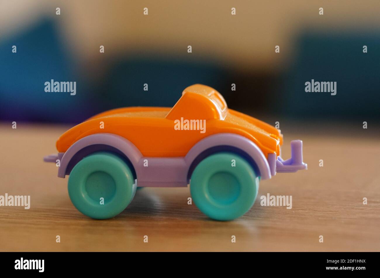 A shallow focus shot of a small plastic toy car on a table with a ...