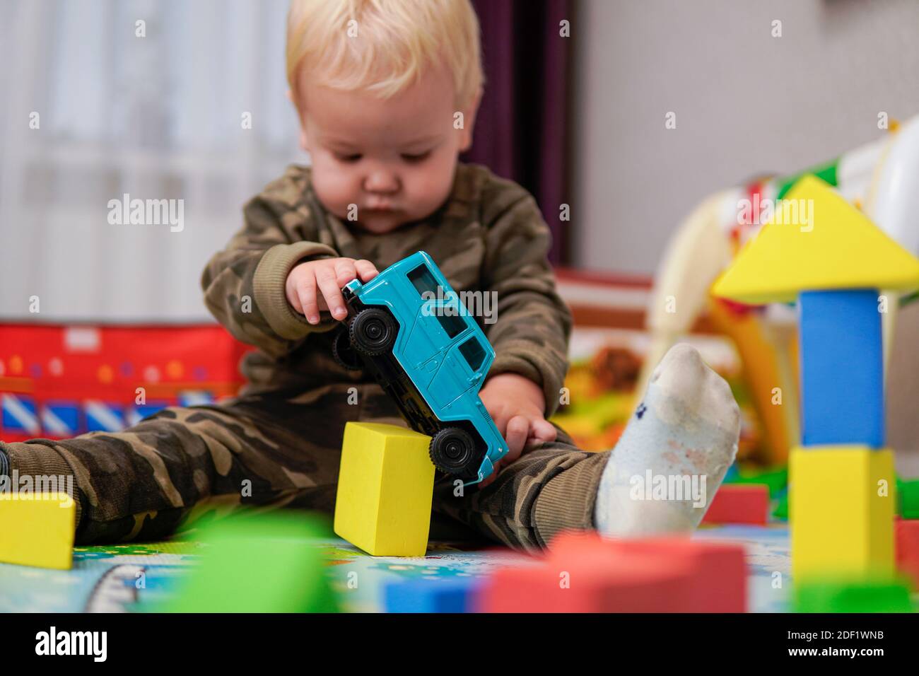 Little boy with blond hair playing with blue car. high quality Stock ...